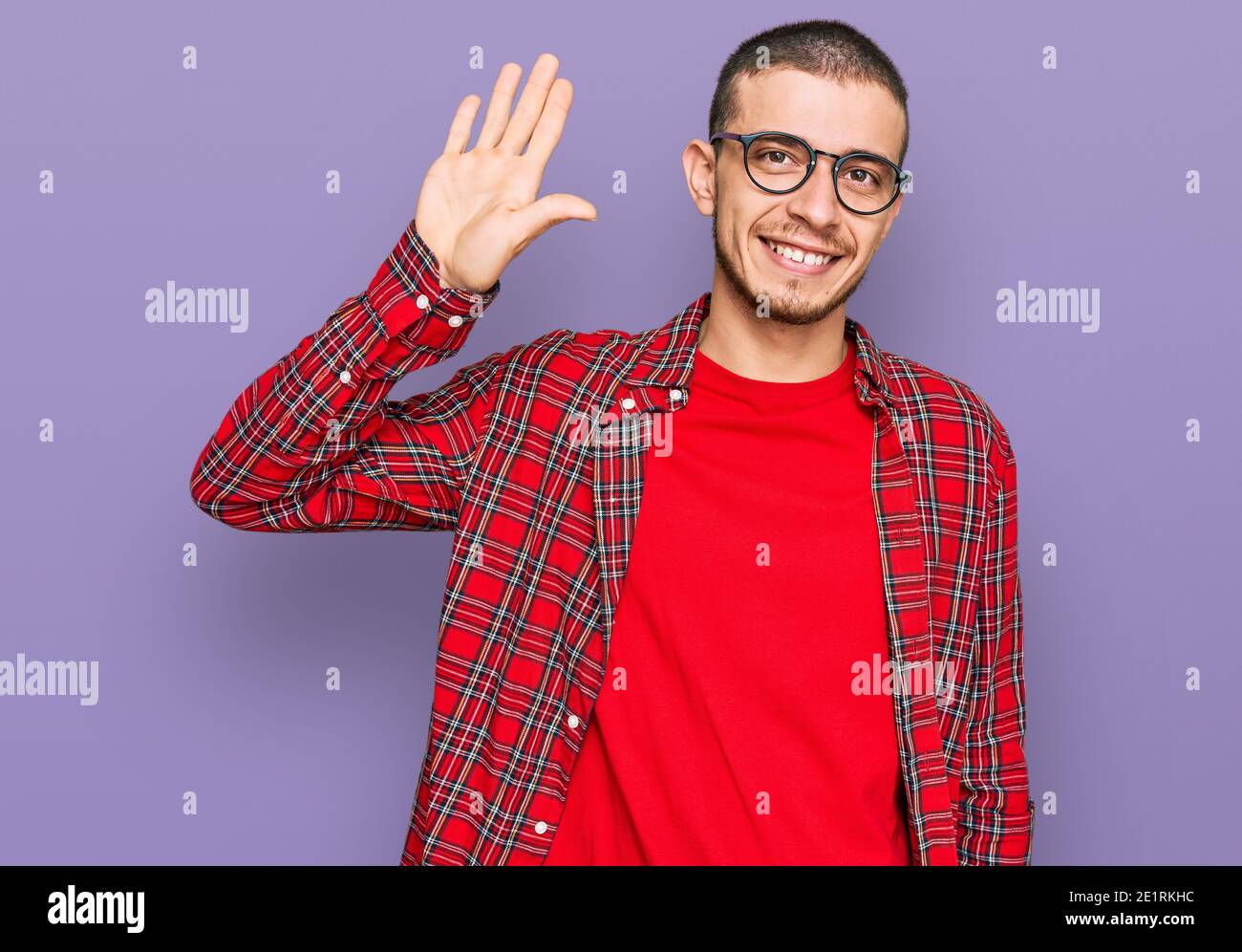 Hispanic young man wearing casual clothes waiving saying hello happy ...