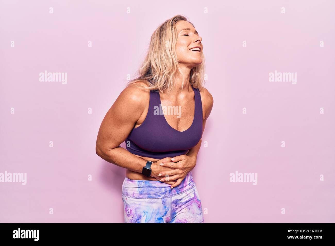 Middle age caucasian blonde woman wearing sportswear over pink ...