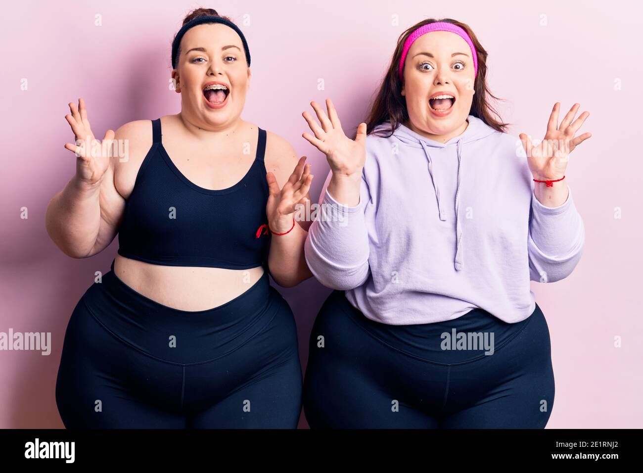 Young plus size twins wearing sportswear celebrating crazy and amazed ...