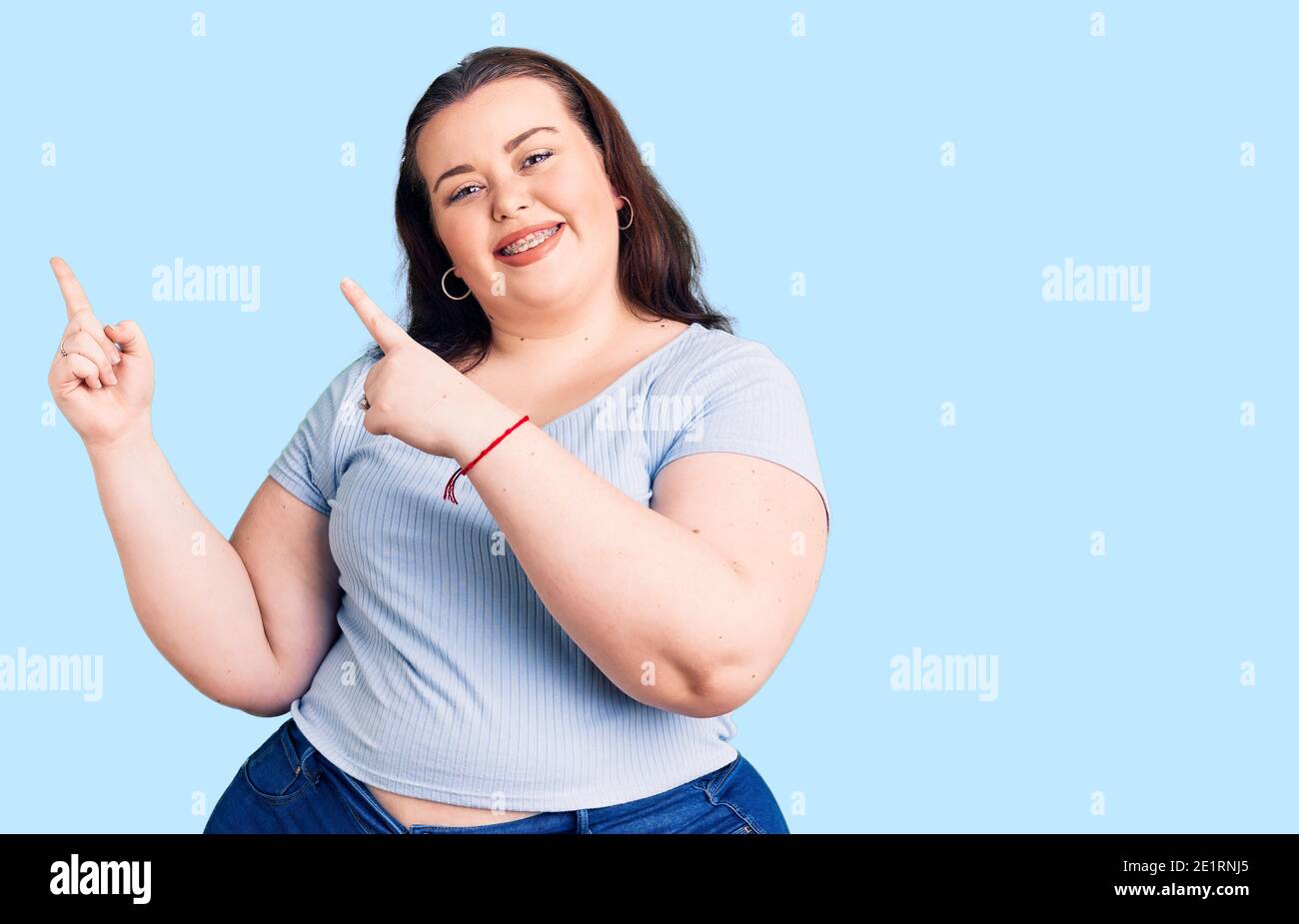 Young plus size woman wearing casual clothes smiling and looking at the ...