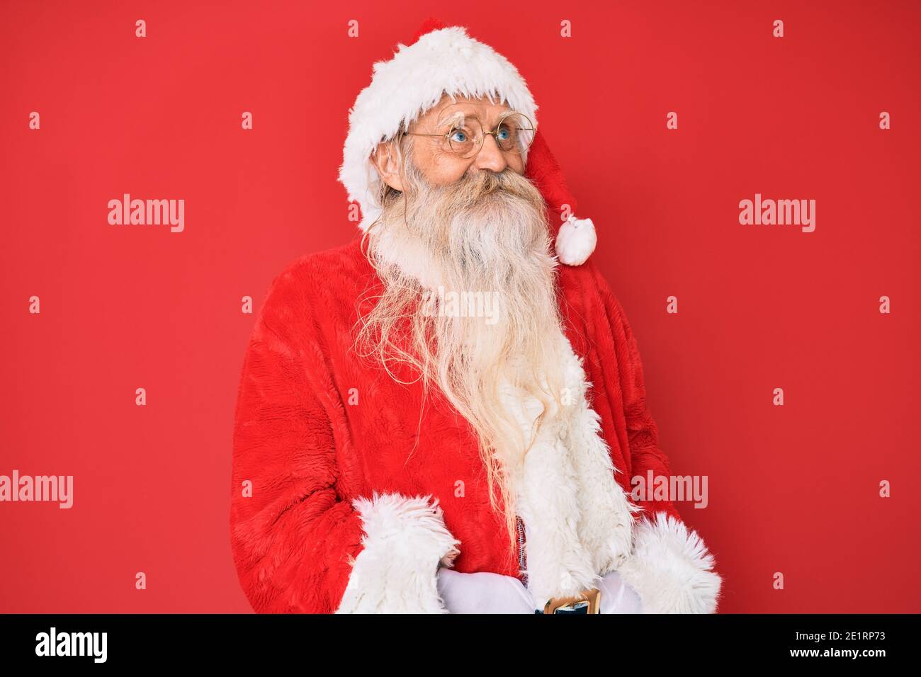 Old senior man with grey hair and long beard wearing traditional santa ...