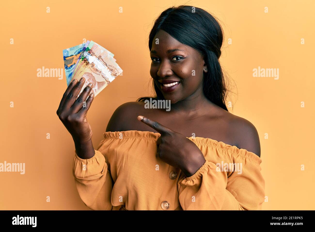 African young woman holding canadian dollars smiling happy pointing ...