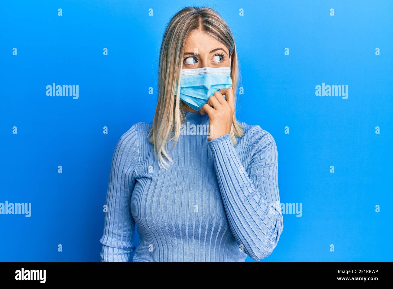 Beautiful blonde woman wearing covid-19 medical mask looking stressed ...
