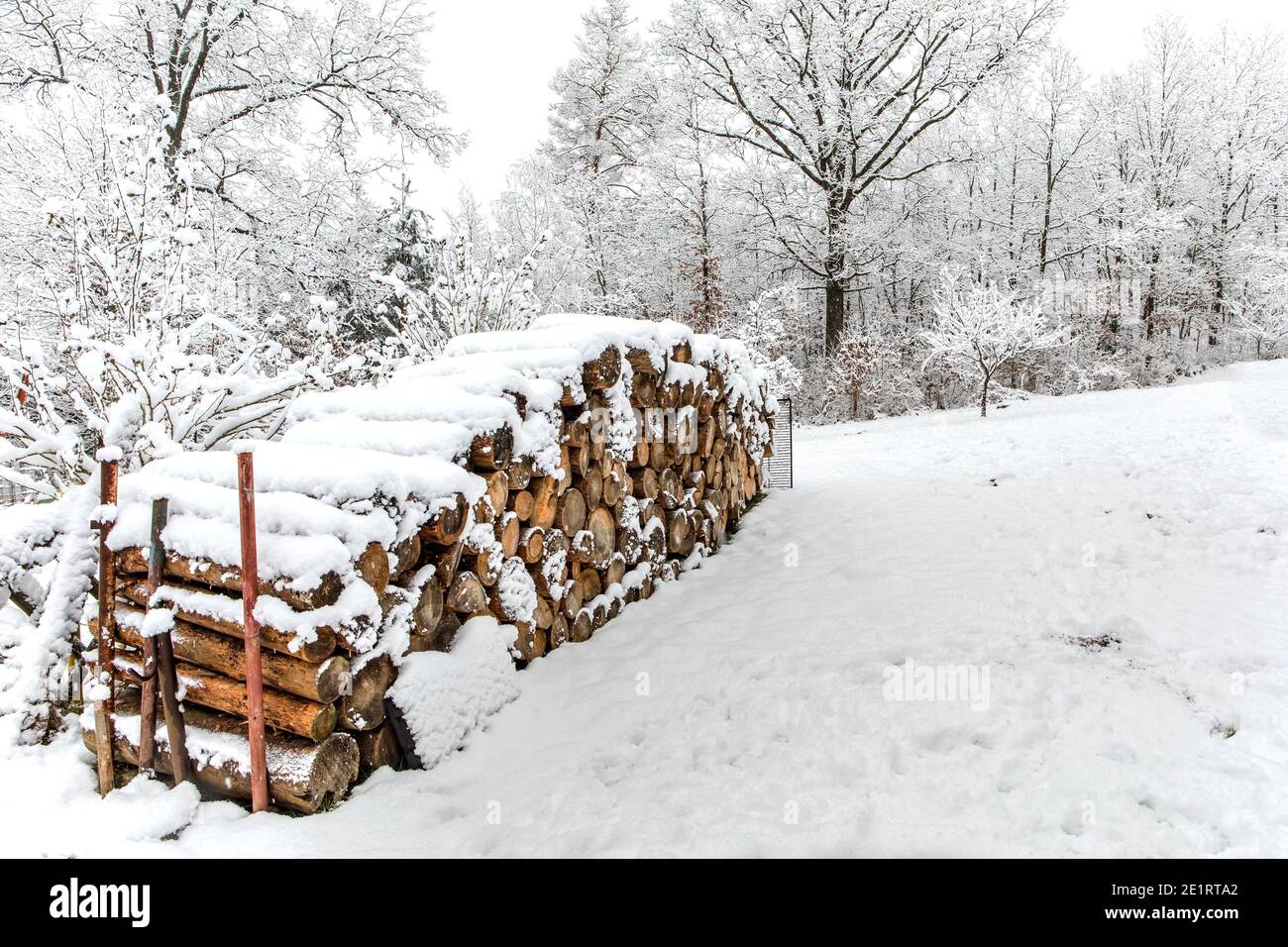 Snow covered firewood stack at winter. Winter village landscape ...