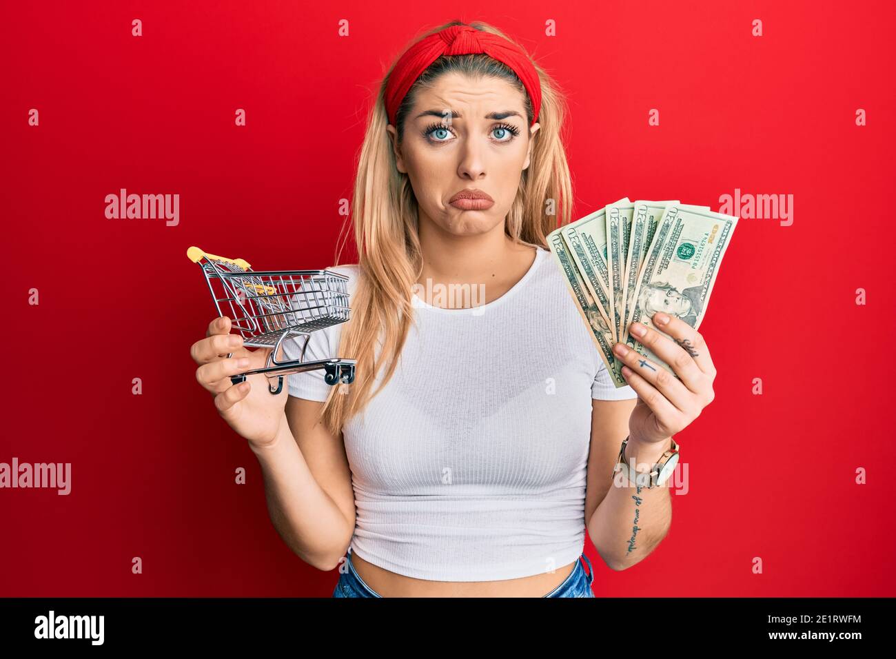Young caucasian woman holding small supermarket shopping cart and ...