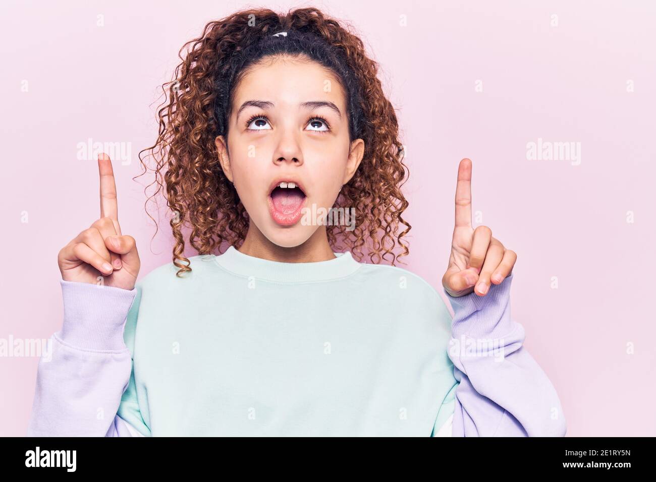 Beautiful kid girl with curly hair wearing casual clothes amazed and ...