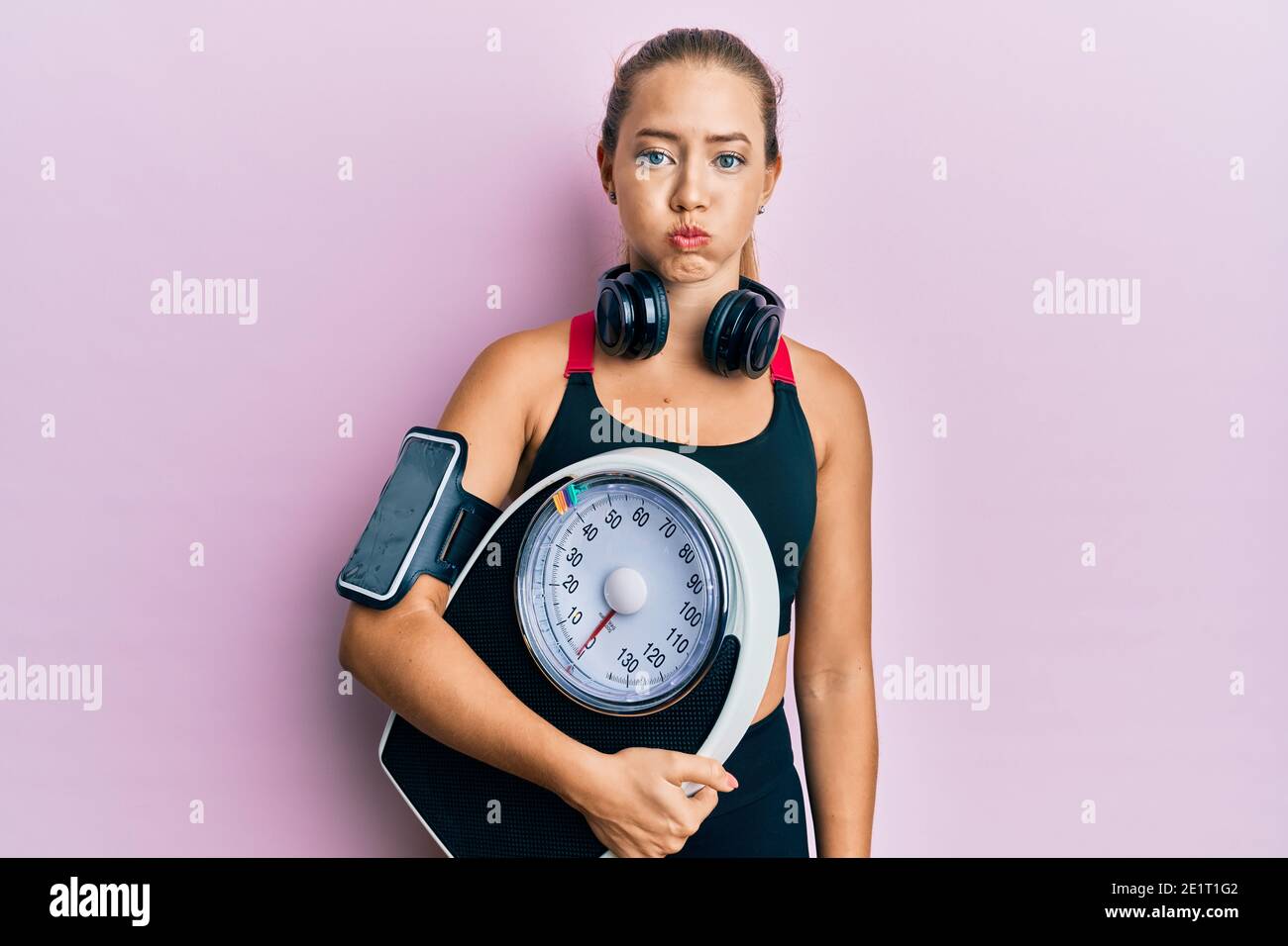 Beautiful young blonde sporty woman holding weight machine to balance ...