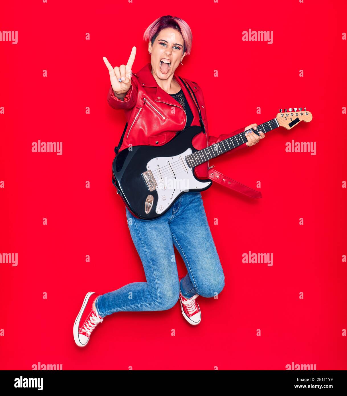 Young beautiful guitarist woman with pink short hair playing electric ...