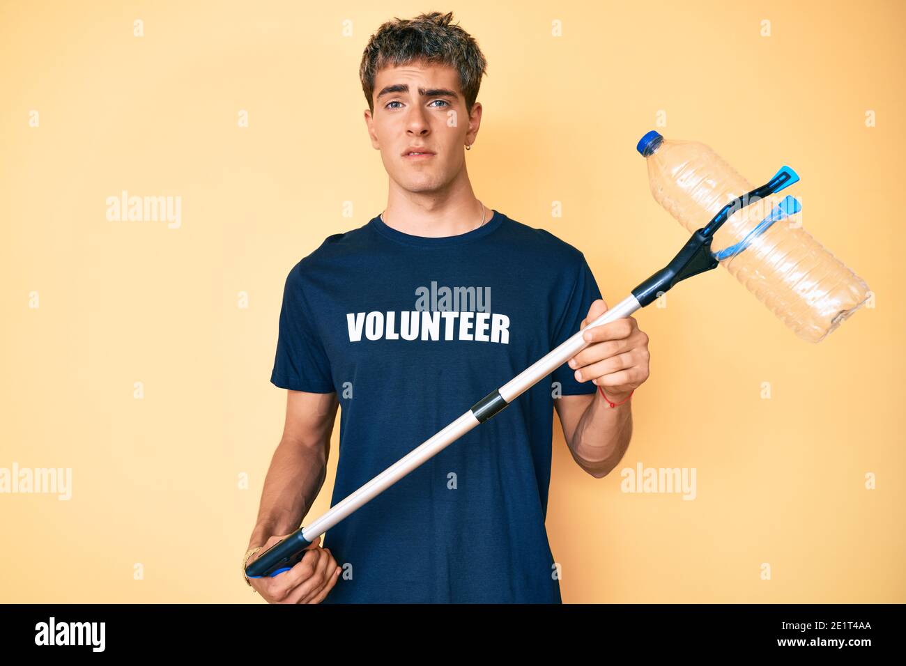 Young handsome man recycling plastic bottle holding litter pick up tool ...