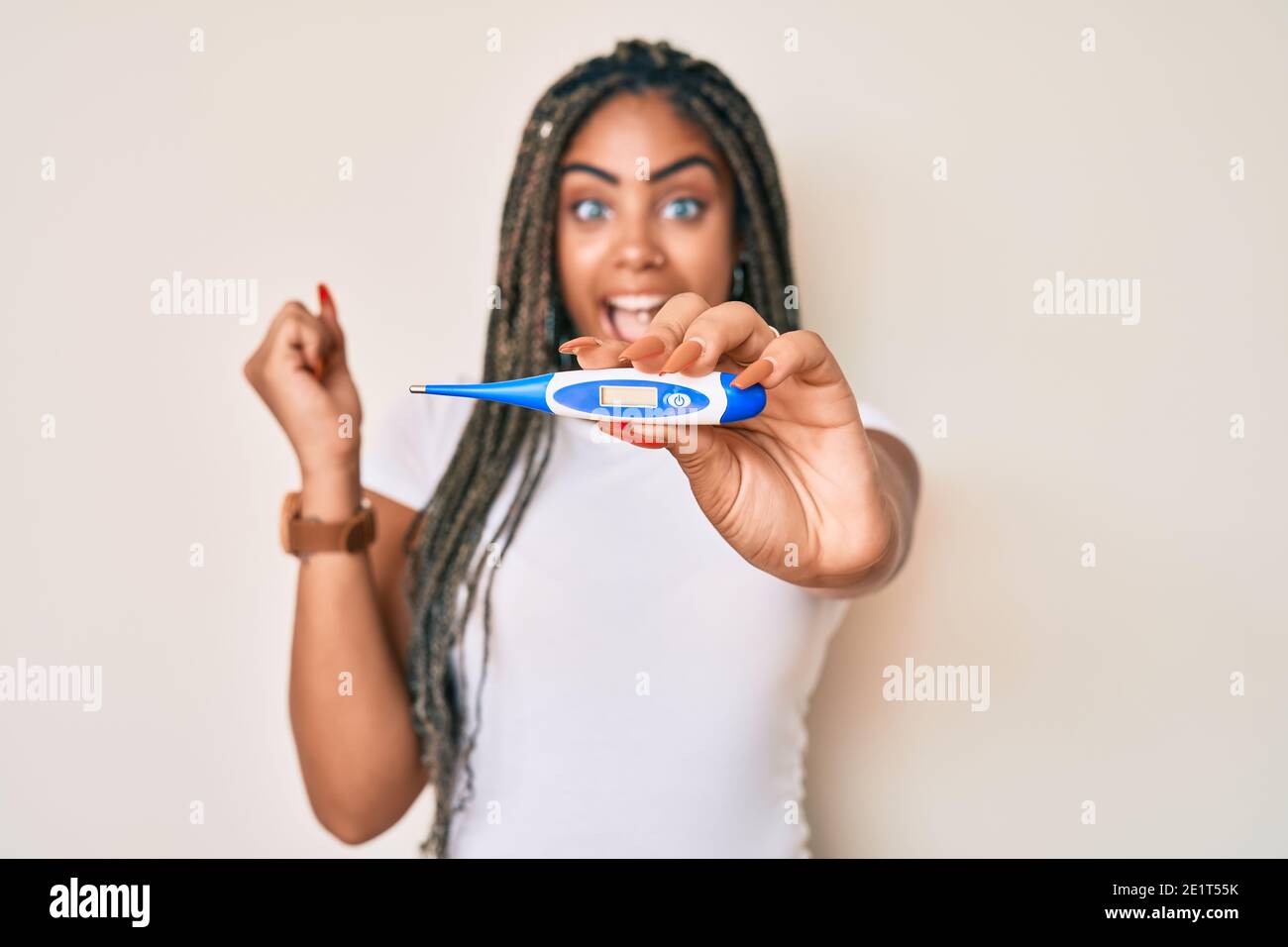 Young african american woman with braids holding thermometer screaming ...
