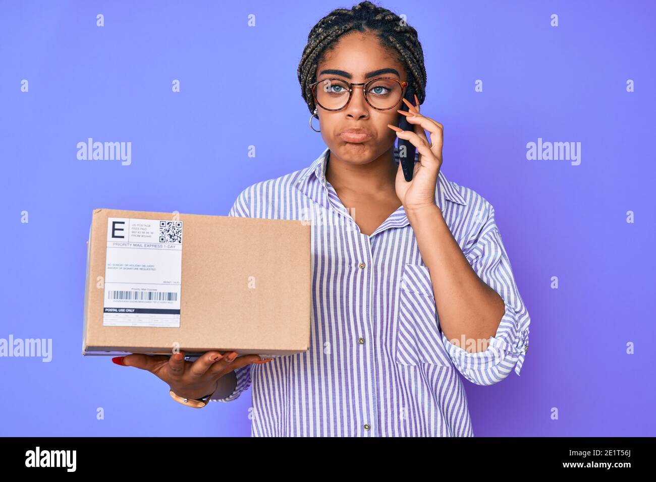 Young african american woman with braids holding delivery box calling ...