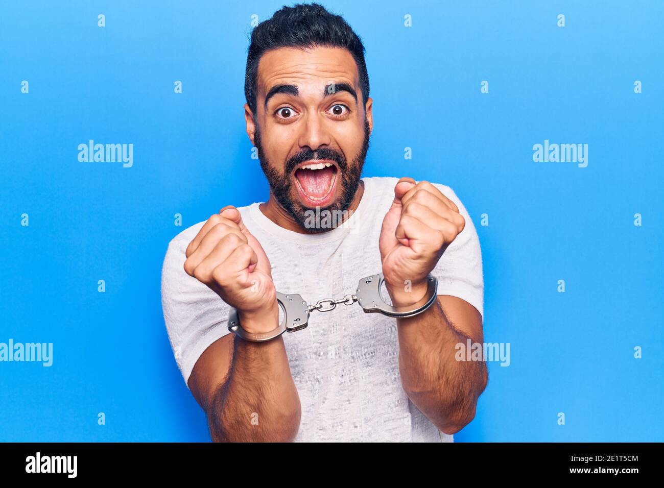 Young hispanic man wearing prisoner handcuffs screaming proud ...