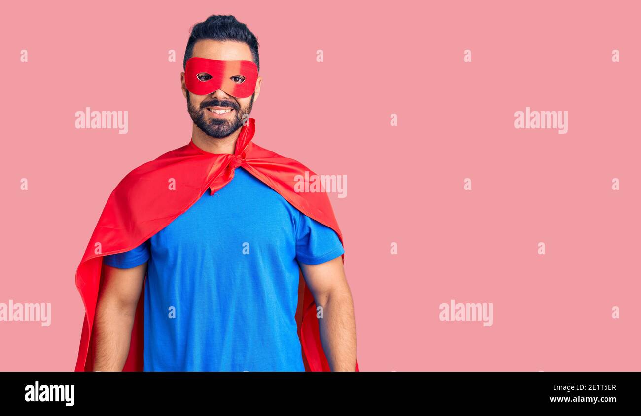 Young hispanic man wearing super hero costume looking positive and ...