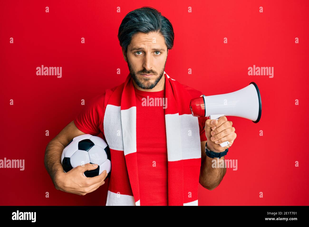 Young hispanic man football hooligan holding ball using megaphone ...