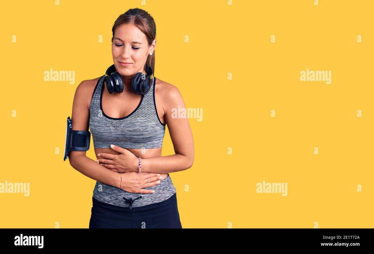 Young beautiful hispanic woman wearing gym clothes and using headphones ...