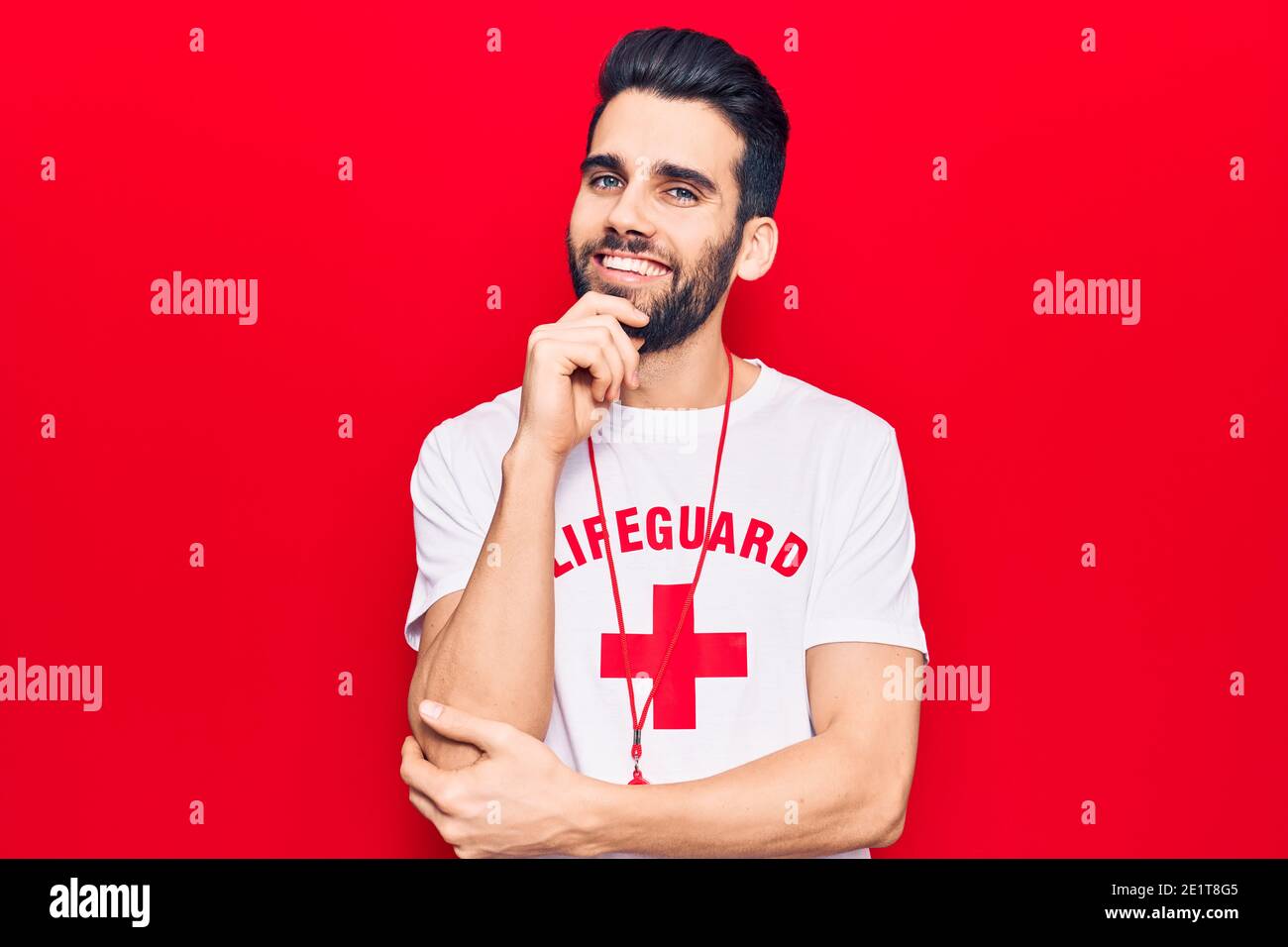 Young handsome man with beard wearing lifeguard t-shirt and whistle ...