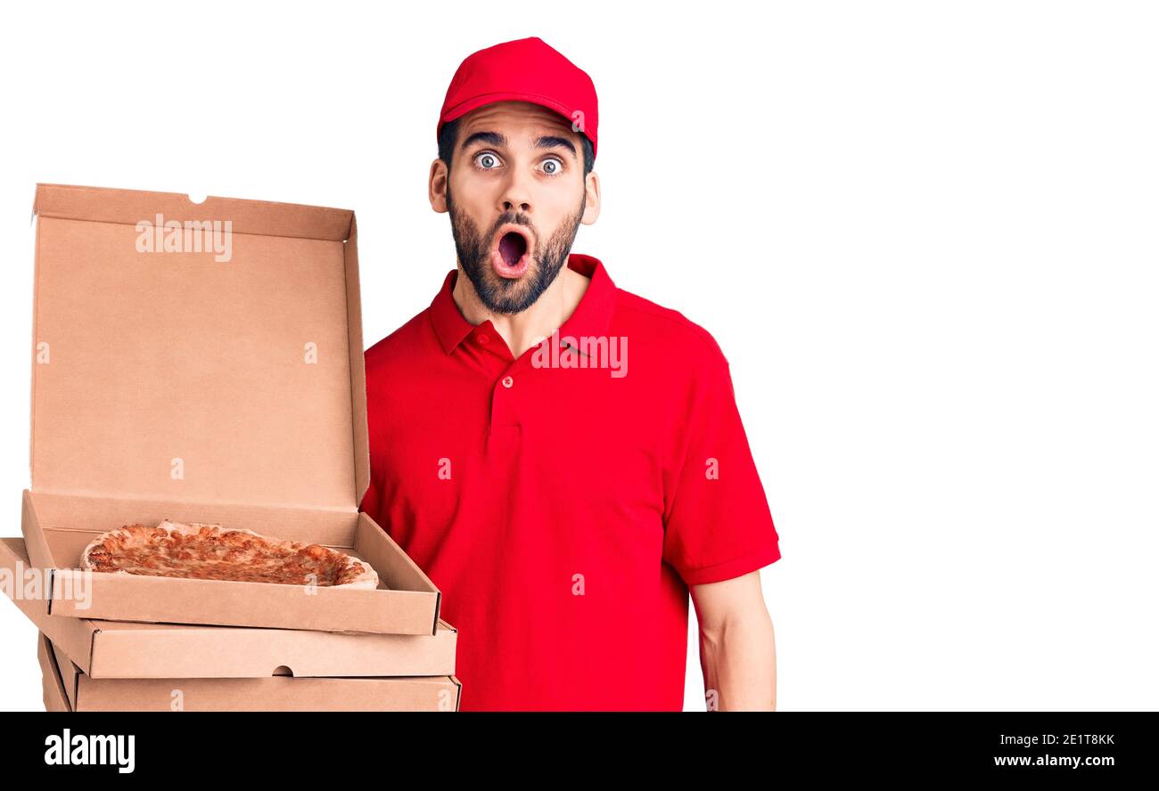 Young handsome man with beard wearing delivery uniform holding boxes ...