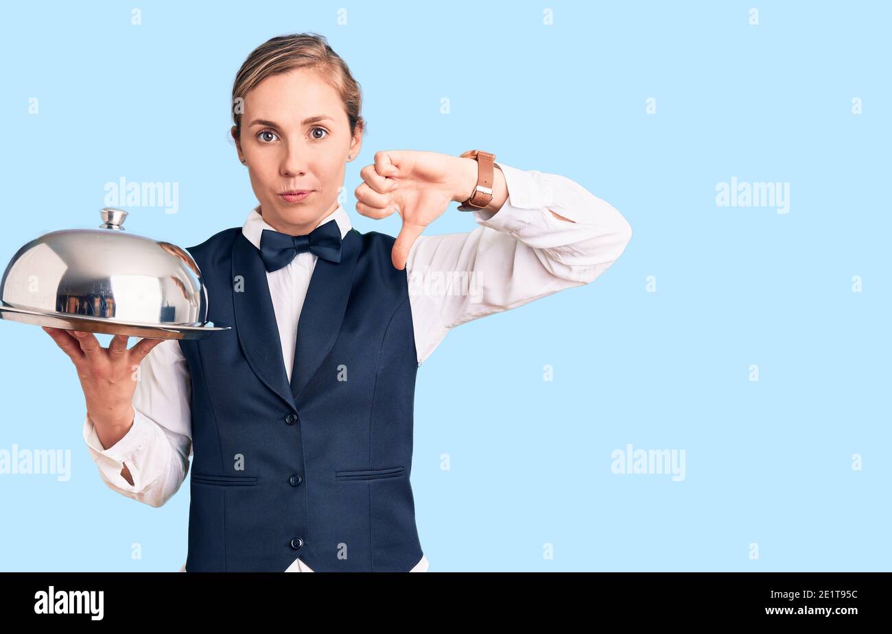 Young beautiful blonde woman wearing waitress uniform holding tray with ...
