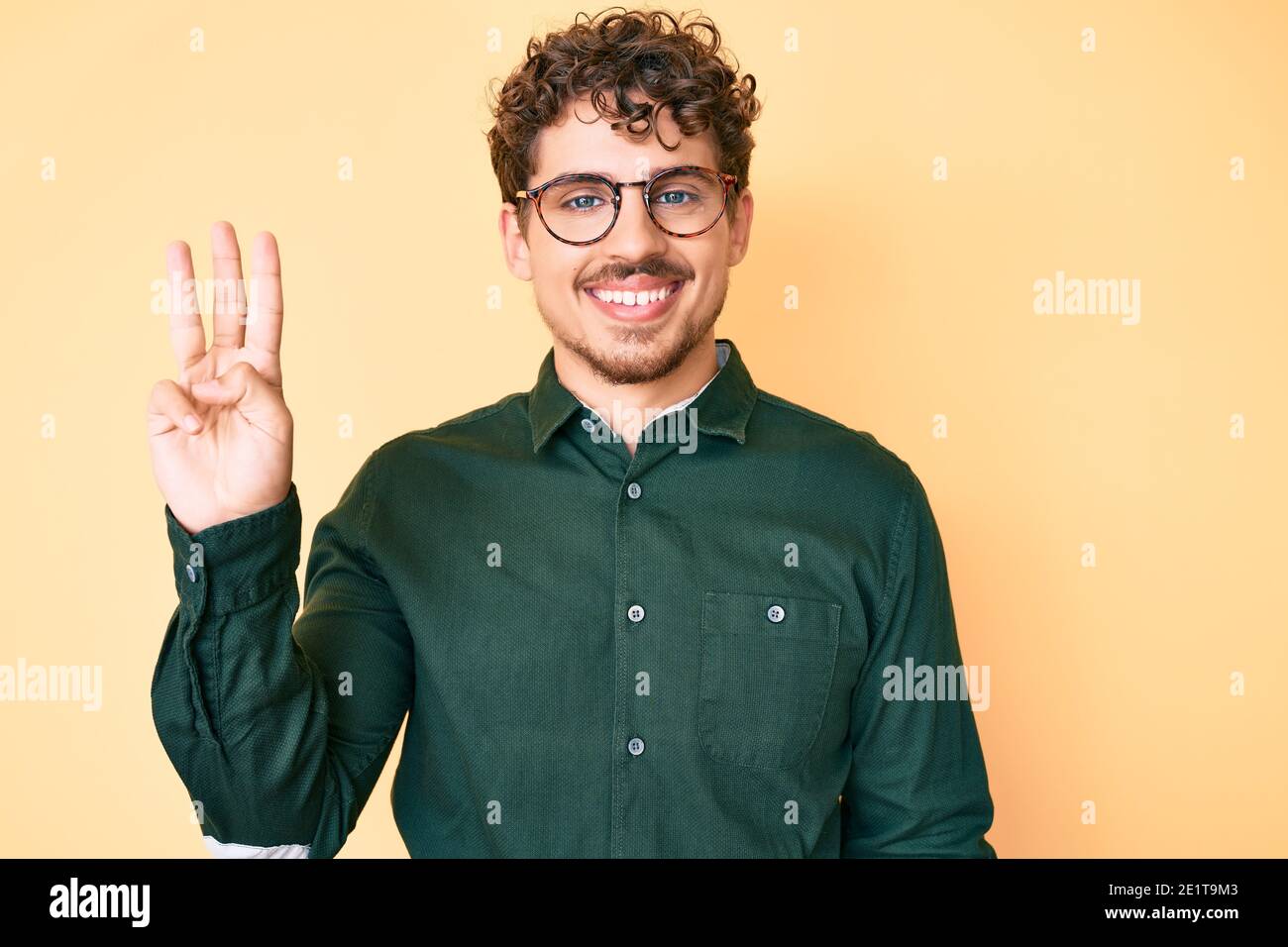 Young caucasian man with curly hair wearing casual clothes and glasses ...