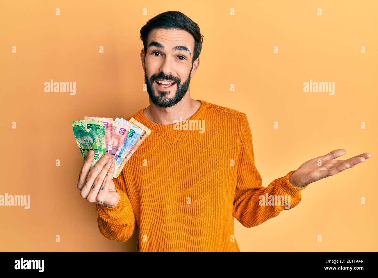 Young hispanic man holding south african rand banknotes celebrating ...