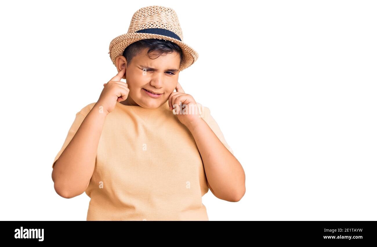 Little boy kid wearing summer hat and hawaiian swimsuit covering ears ...
