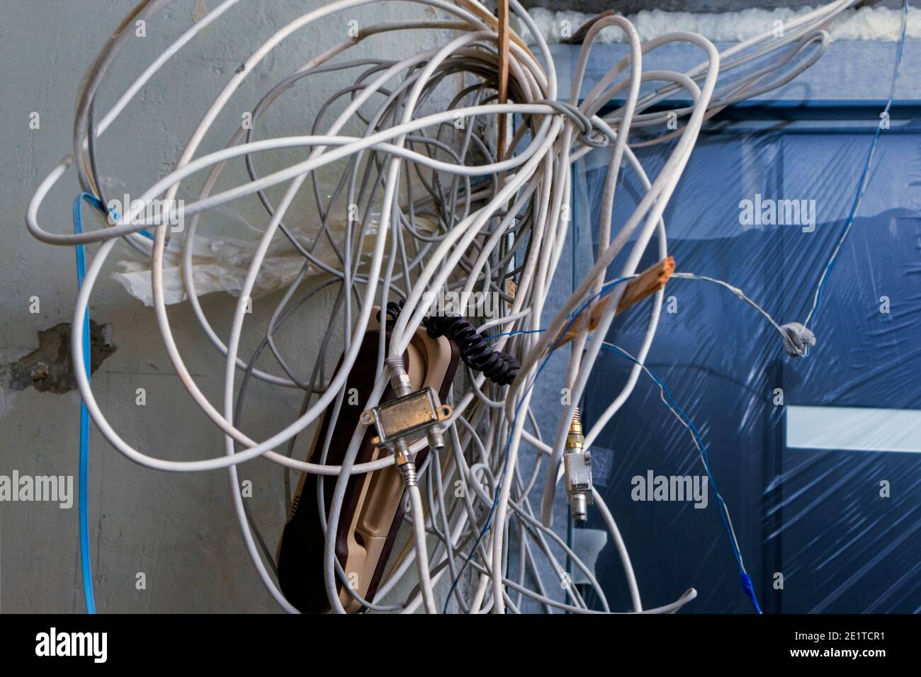 Mess of tangled cables and telephone hanging on the wall, shallow DOF Stock Photo - Alamy