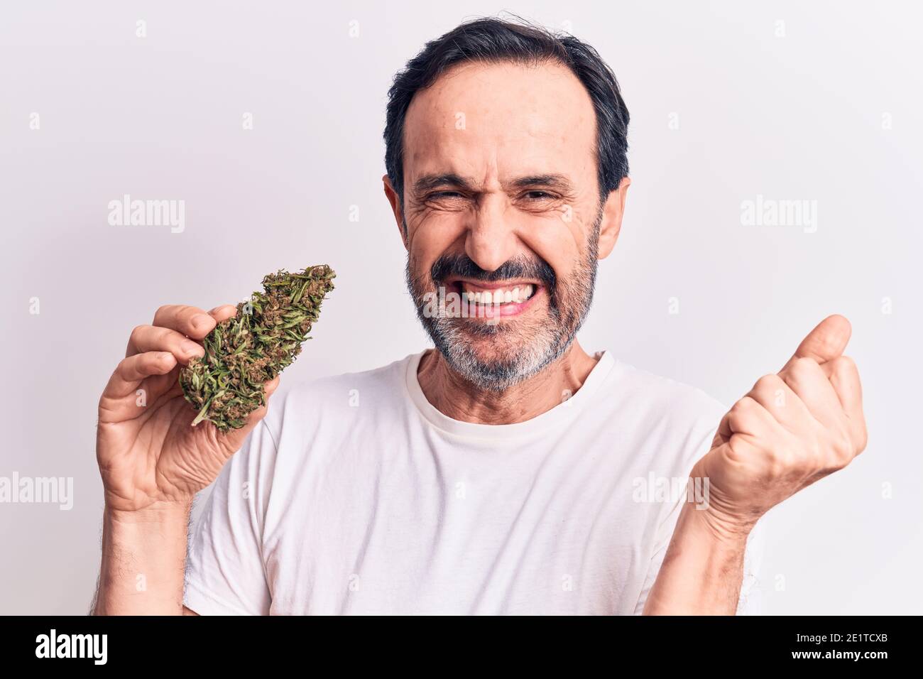 Middle age handsome man holding cannabis weed standing over isolated ...