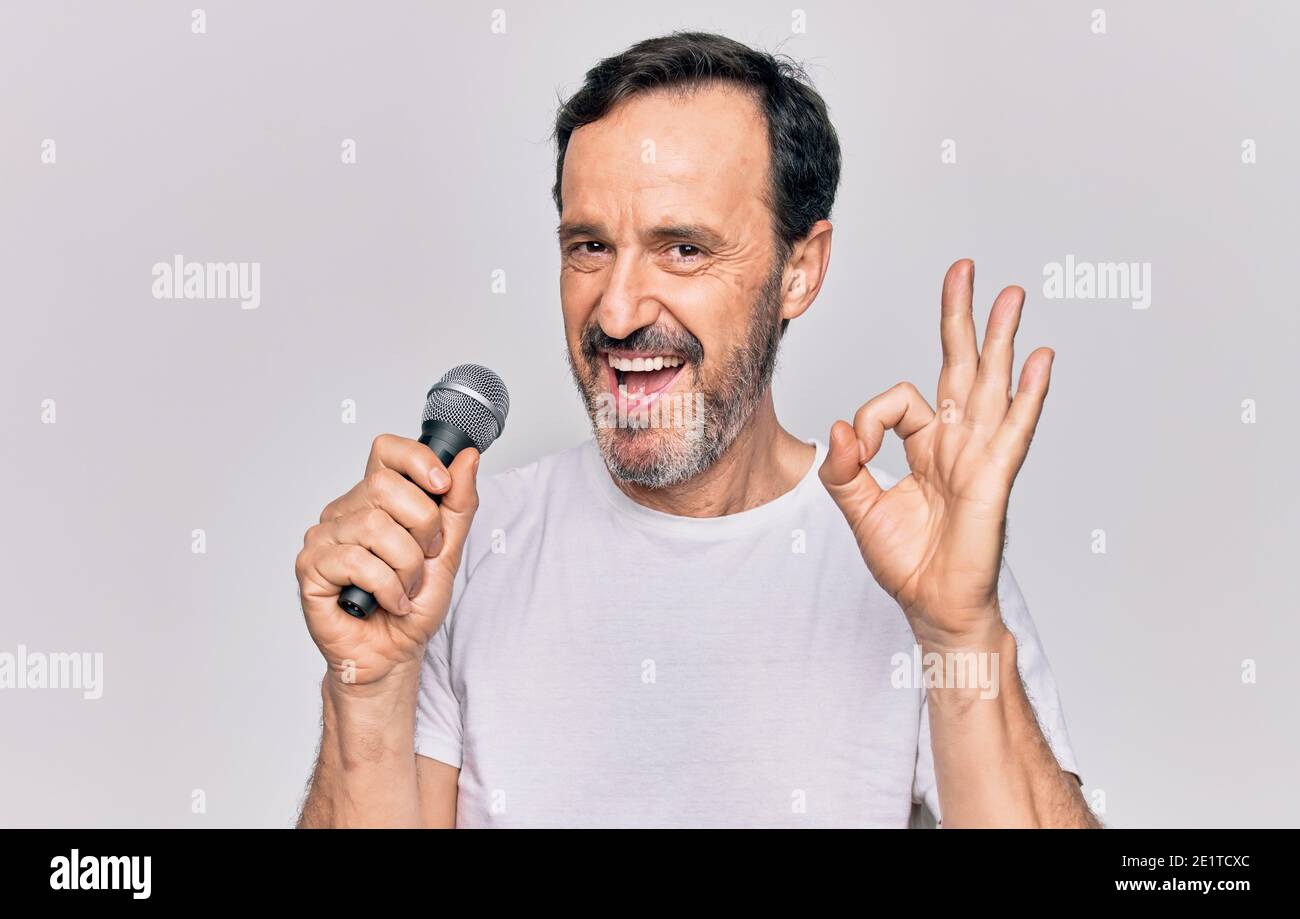 Middle age handsome singer man singing using microphone over isolated ...