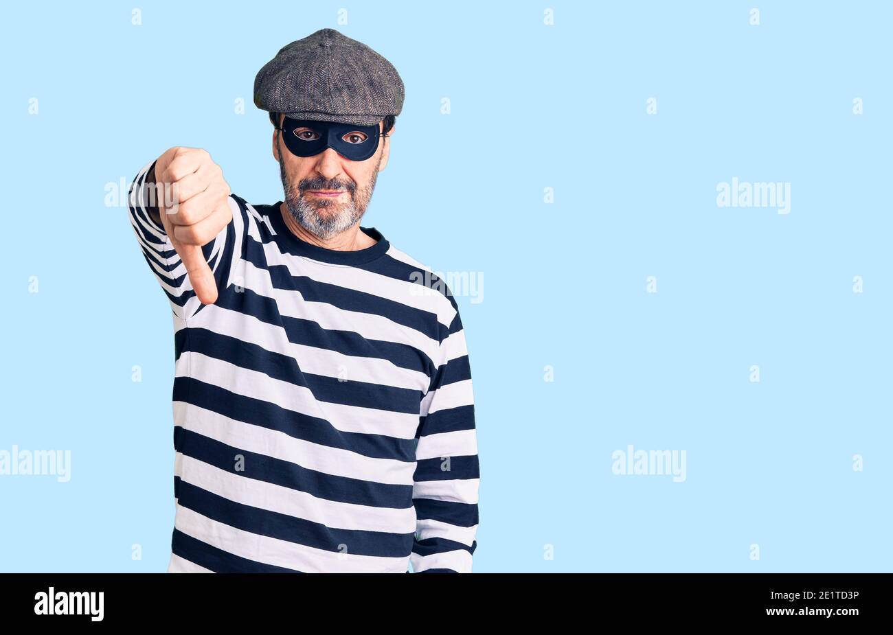Middle age handsome man wearing burglar mask looking unhappy and angry ...