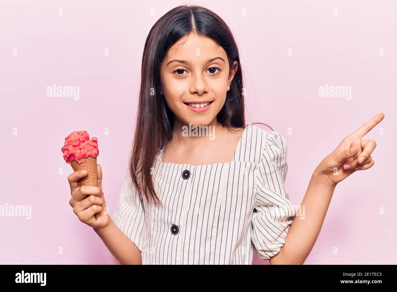 Beautiful child girl holding ice cream smiling happy pointing with hand ...
