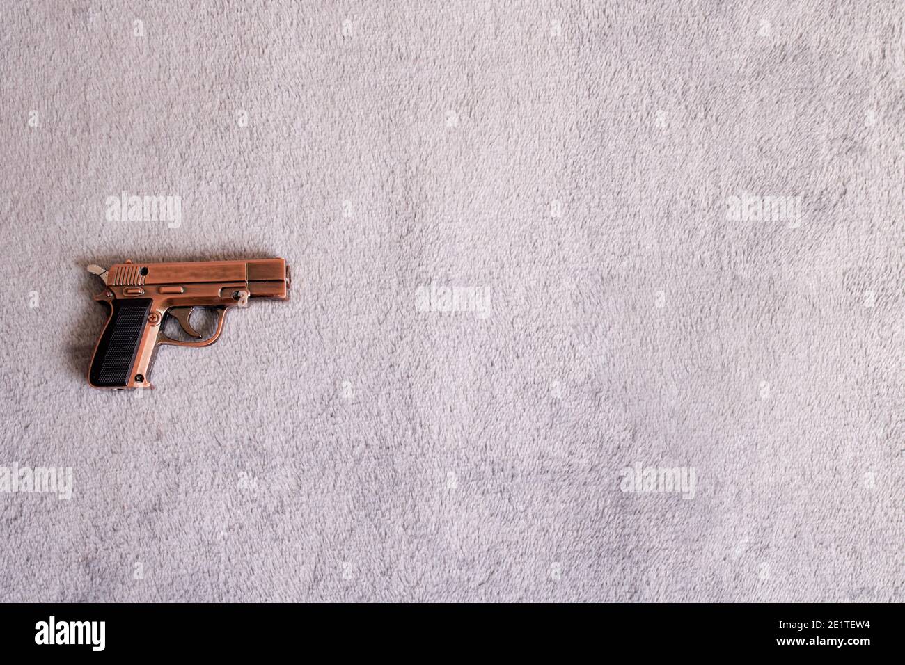 Metal fake pistol on a gray background, copy space Stock Photo - Alamy