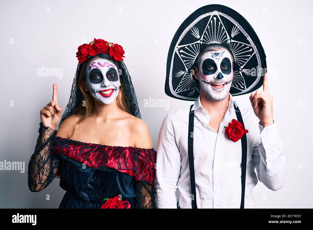 Couple wearing day of the dead costume over white smiling with an idea ...