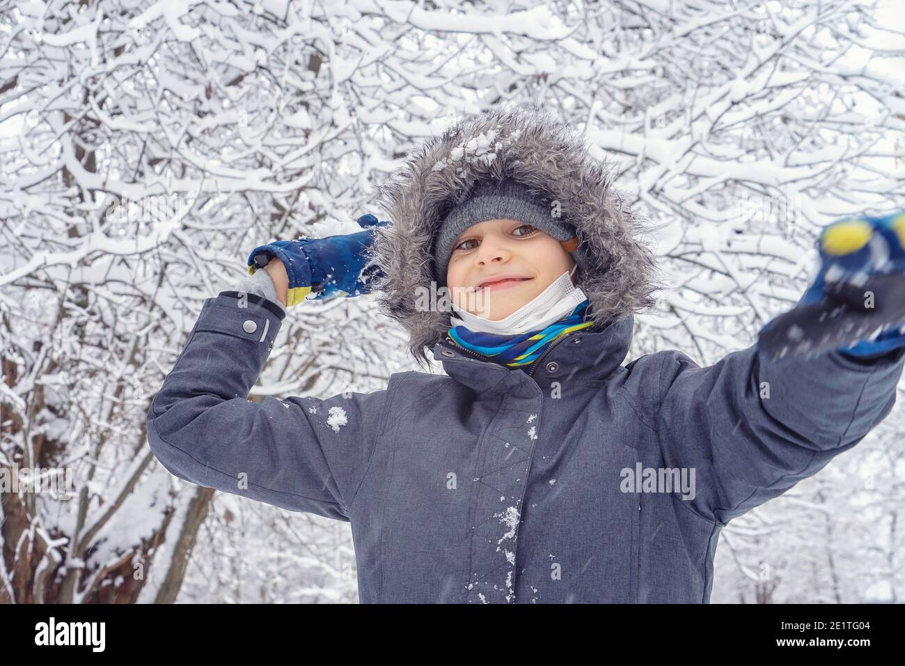 Kid boy wearing medical protective mask playing snowball. Active winter ...