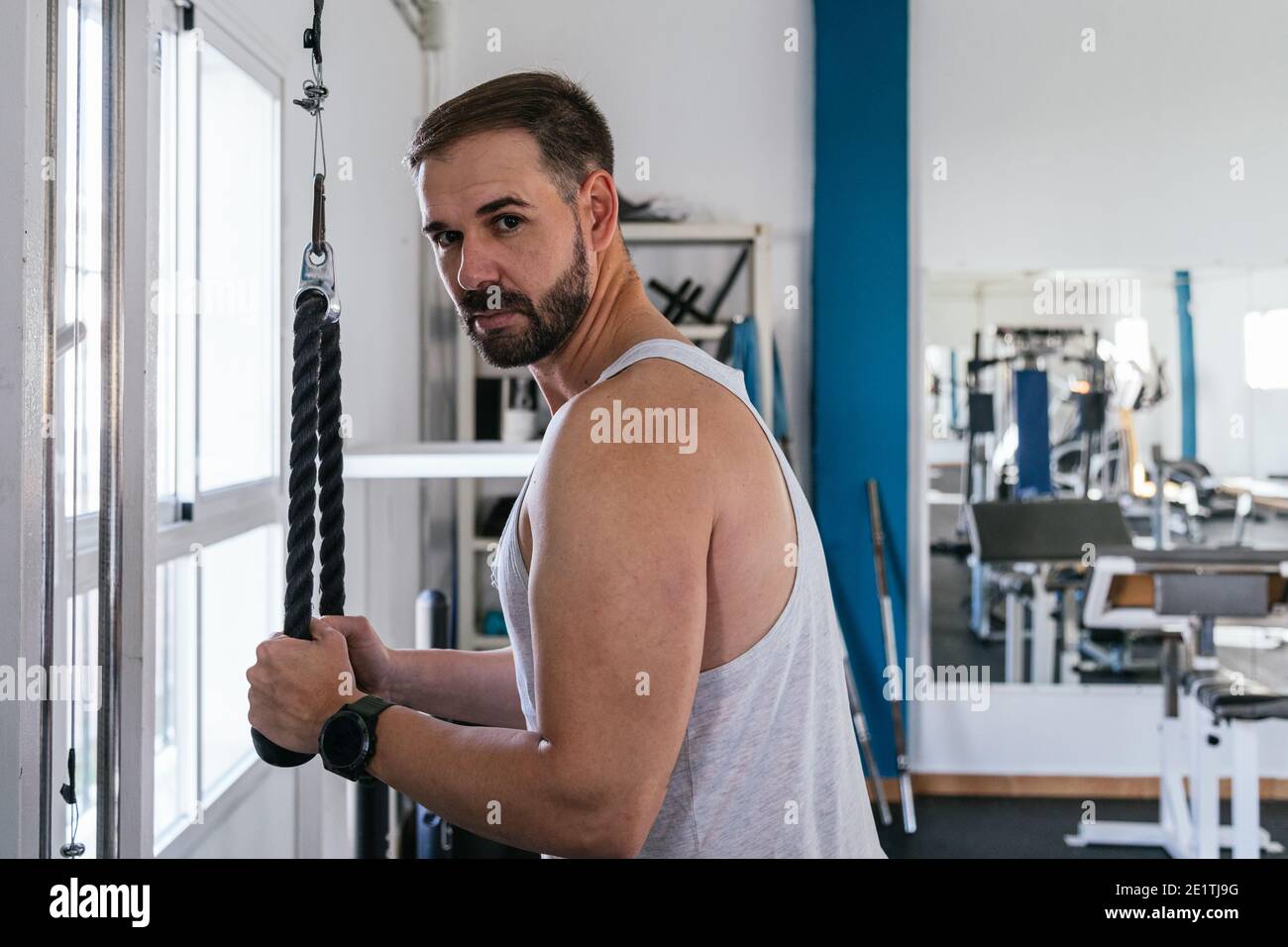 Man in a gym making triceps with ropes. GYM concept Stock Photo - Alamy