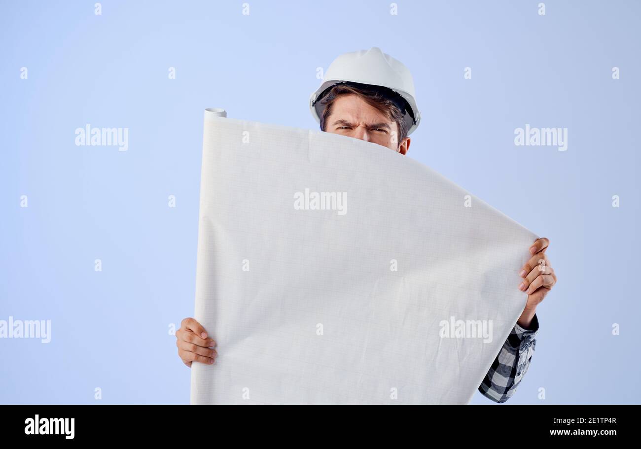 A man in a working uniform an engineer blueprints a project plan ...