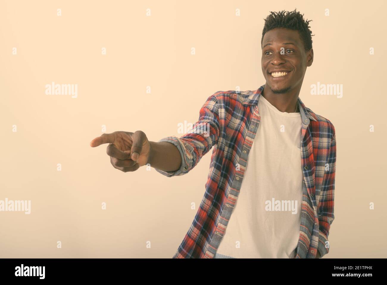 Studio shot of young happy black African man smiling while pointing at ...