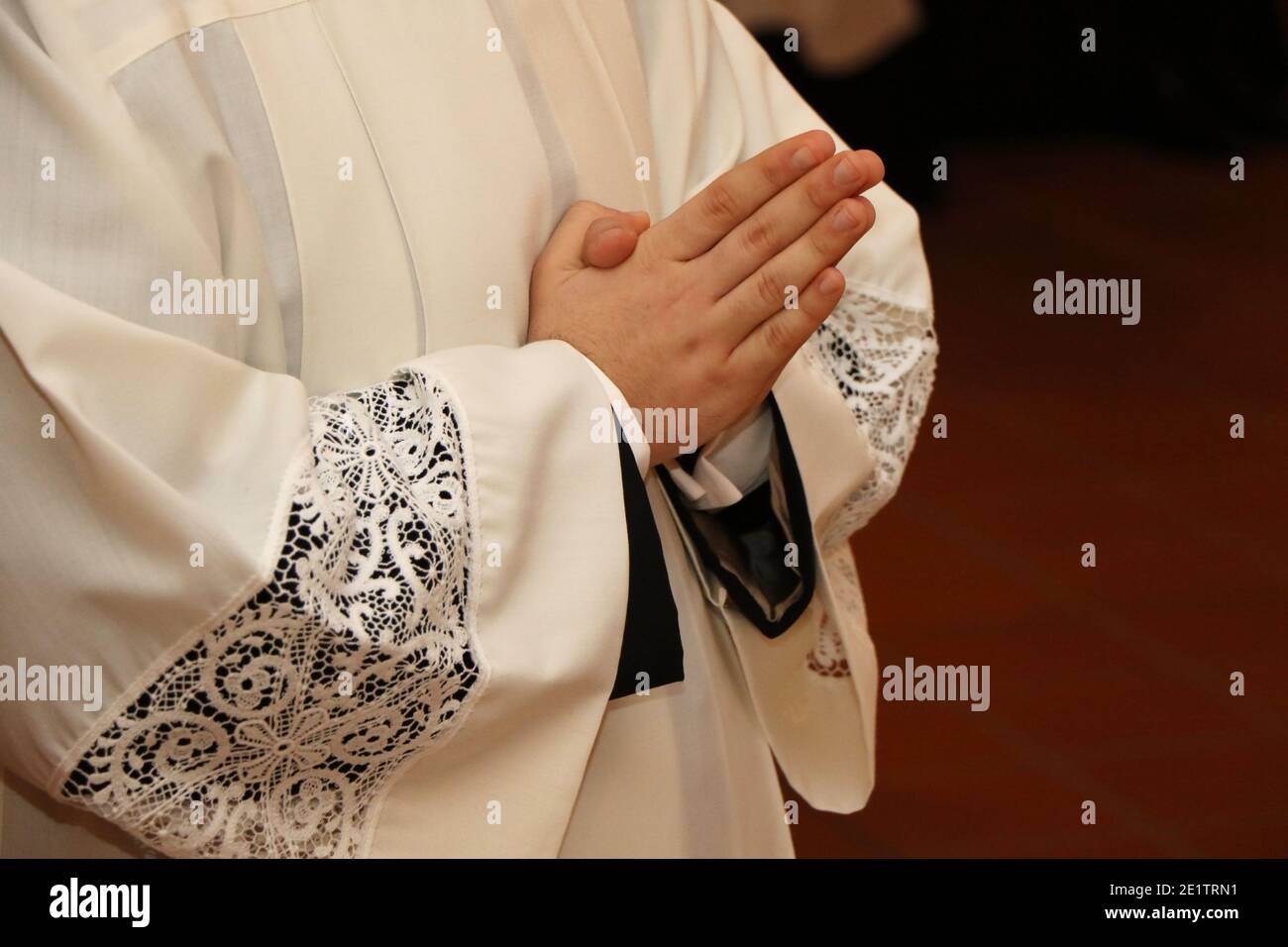 Young priest with his hands folded in prayer Stock Photo - Alamy