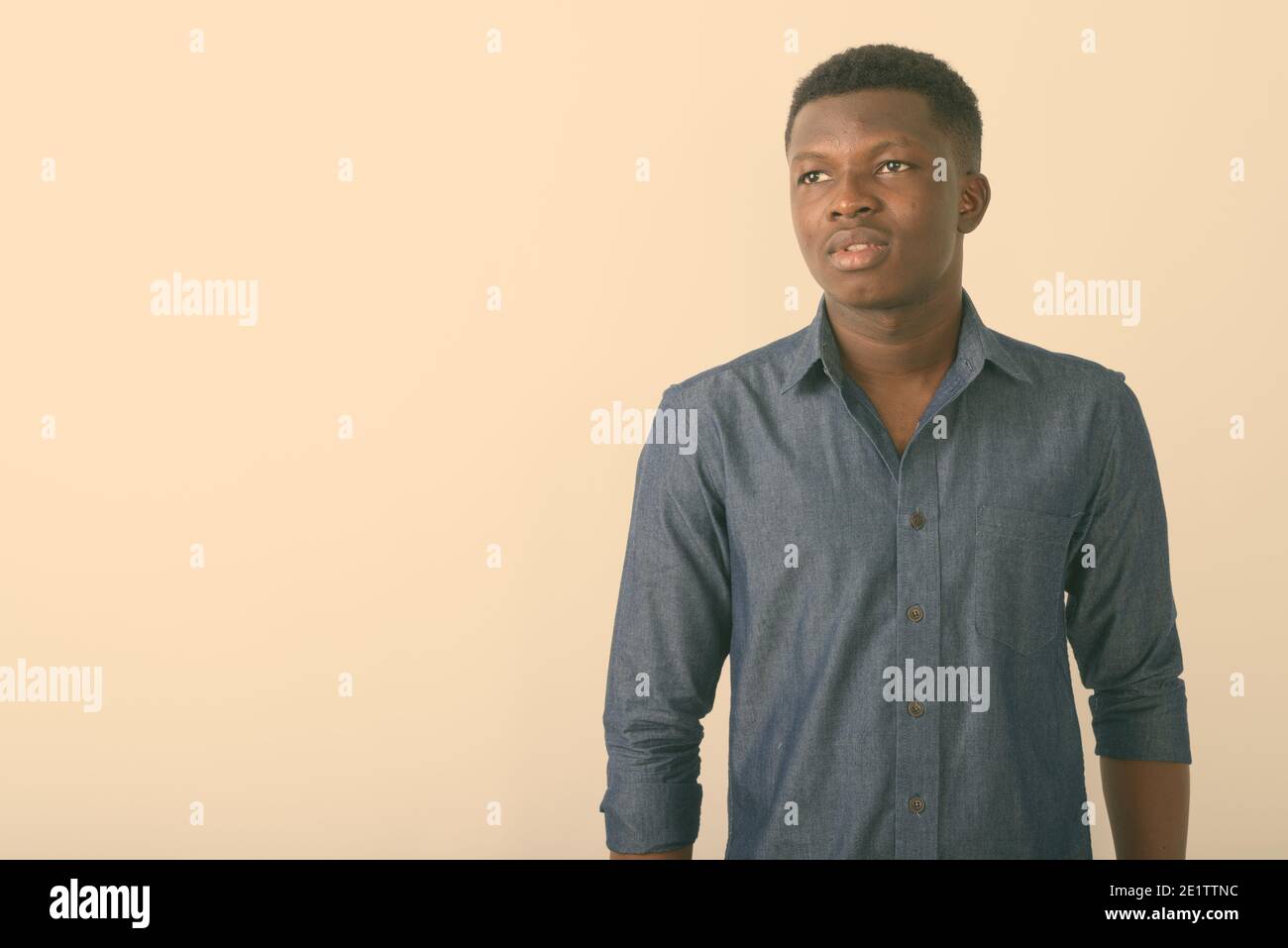 Studio shot of young black African man thinking while looking up ...