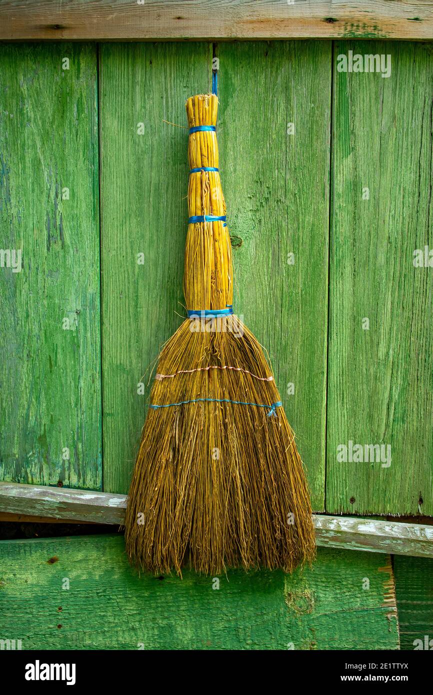 A cleaning broom leaning against a green wooden wall ... of an old ...