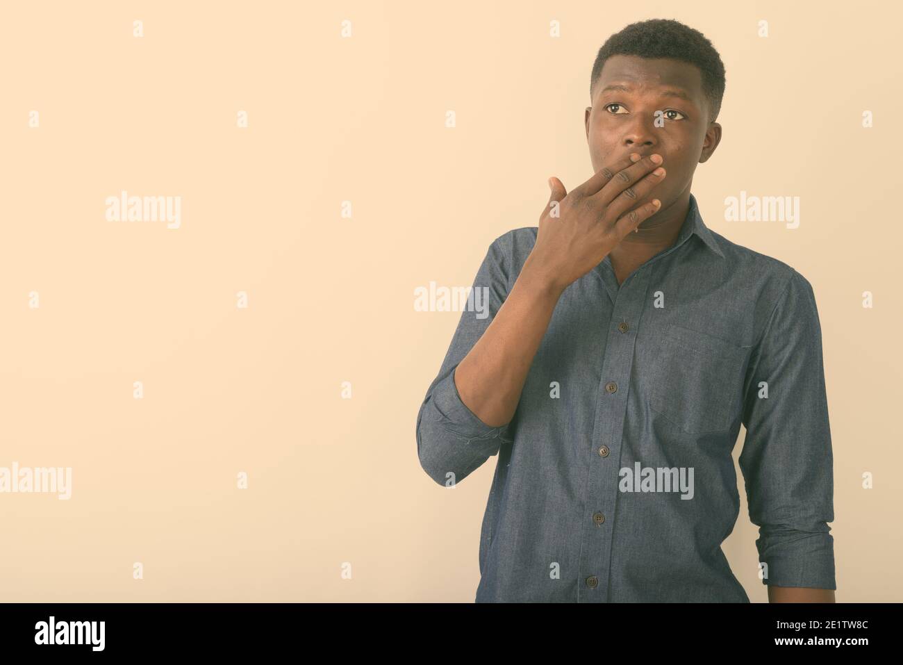 Studio shot of young black African man thinking and looking shocked ...