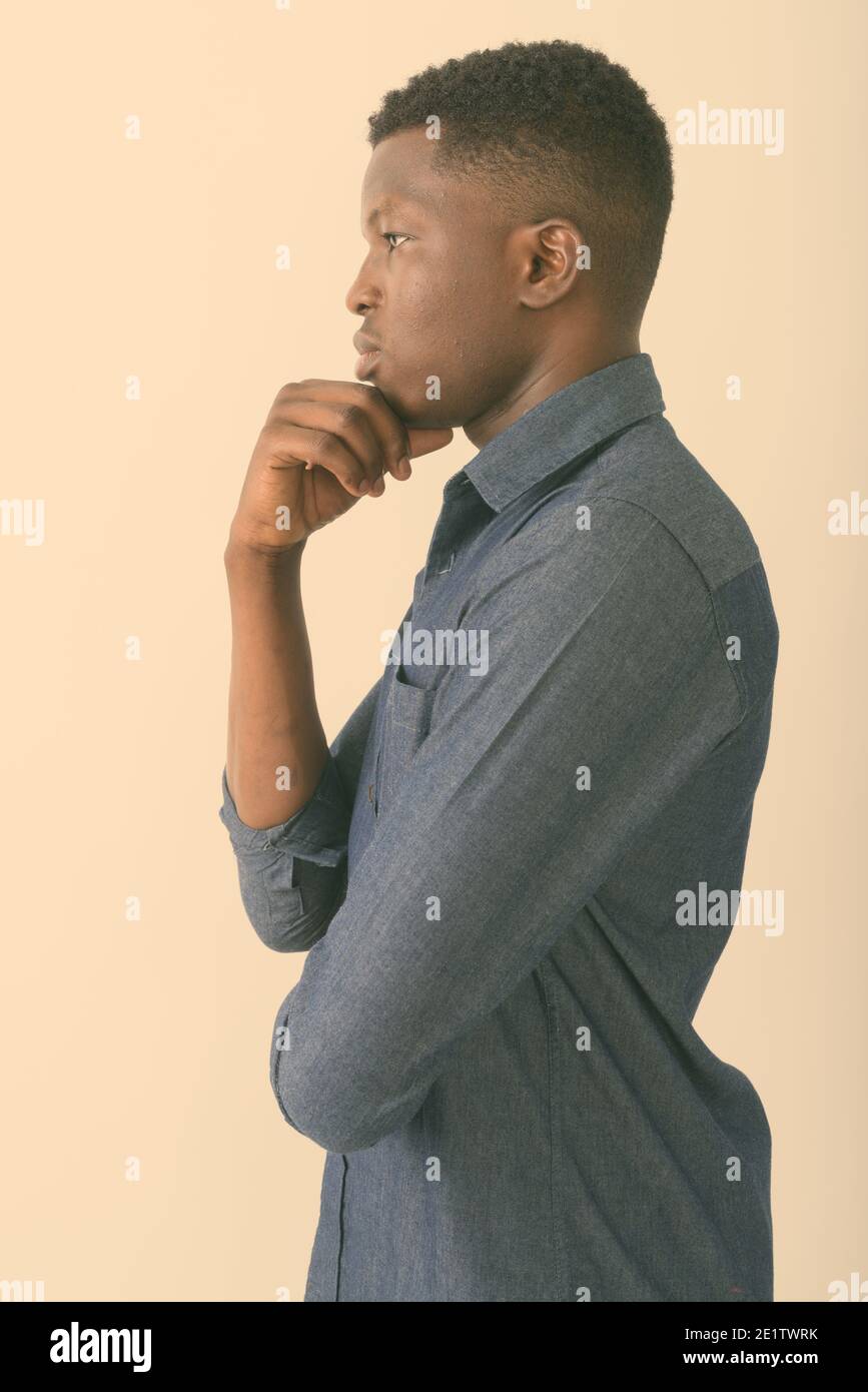 Profile view of young black African man thinking against white ...
