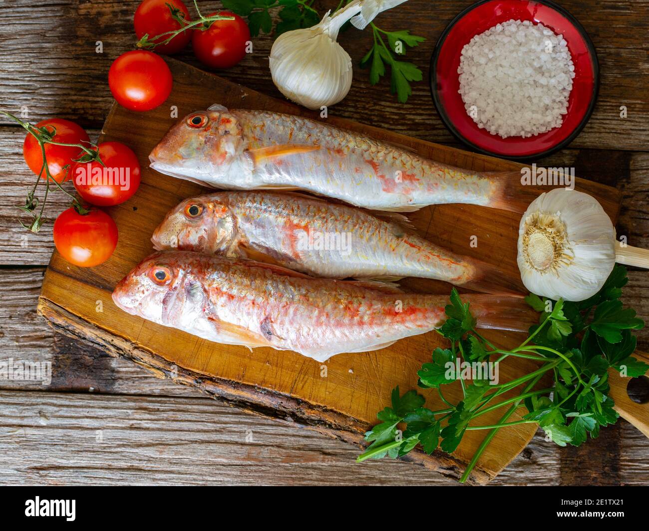 red mullet on an old wooden board background with typical ingredients ...