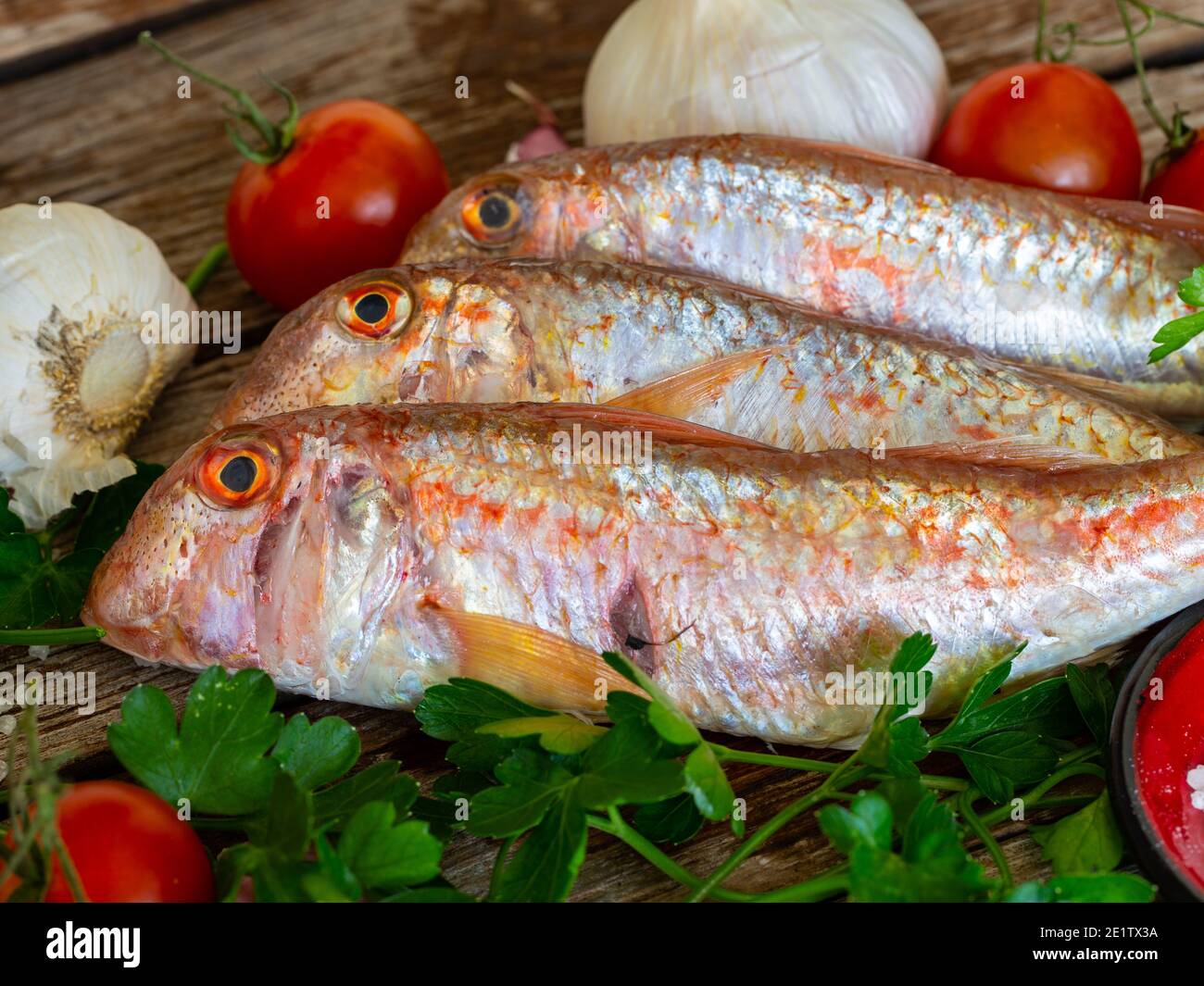 red mullet on an old wooden board background with typical ingredients ...