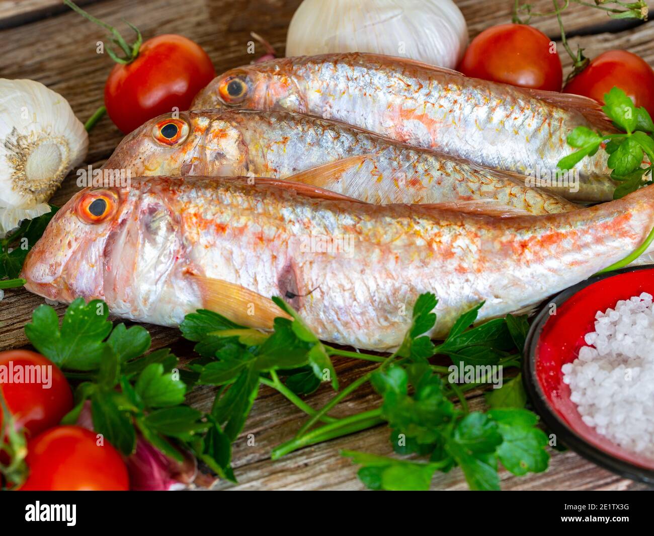 red mullet on an old wooden board background with typical ingredients ...