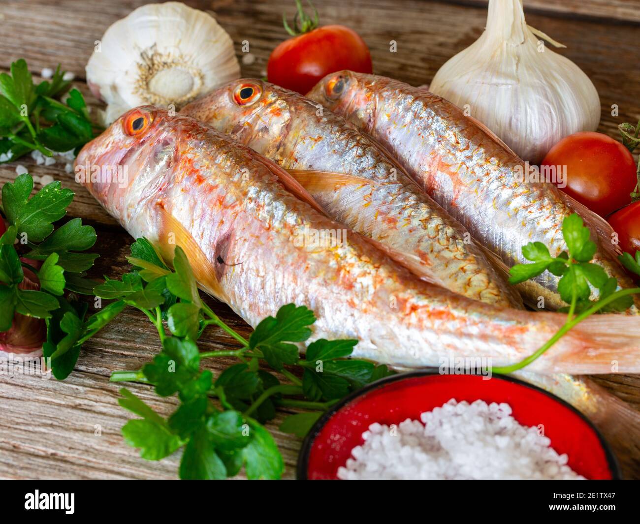 red mullet on an old wooden board background with typical ingredients ...