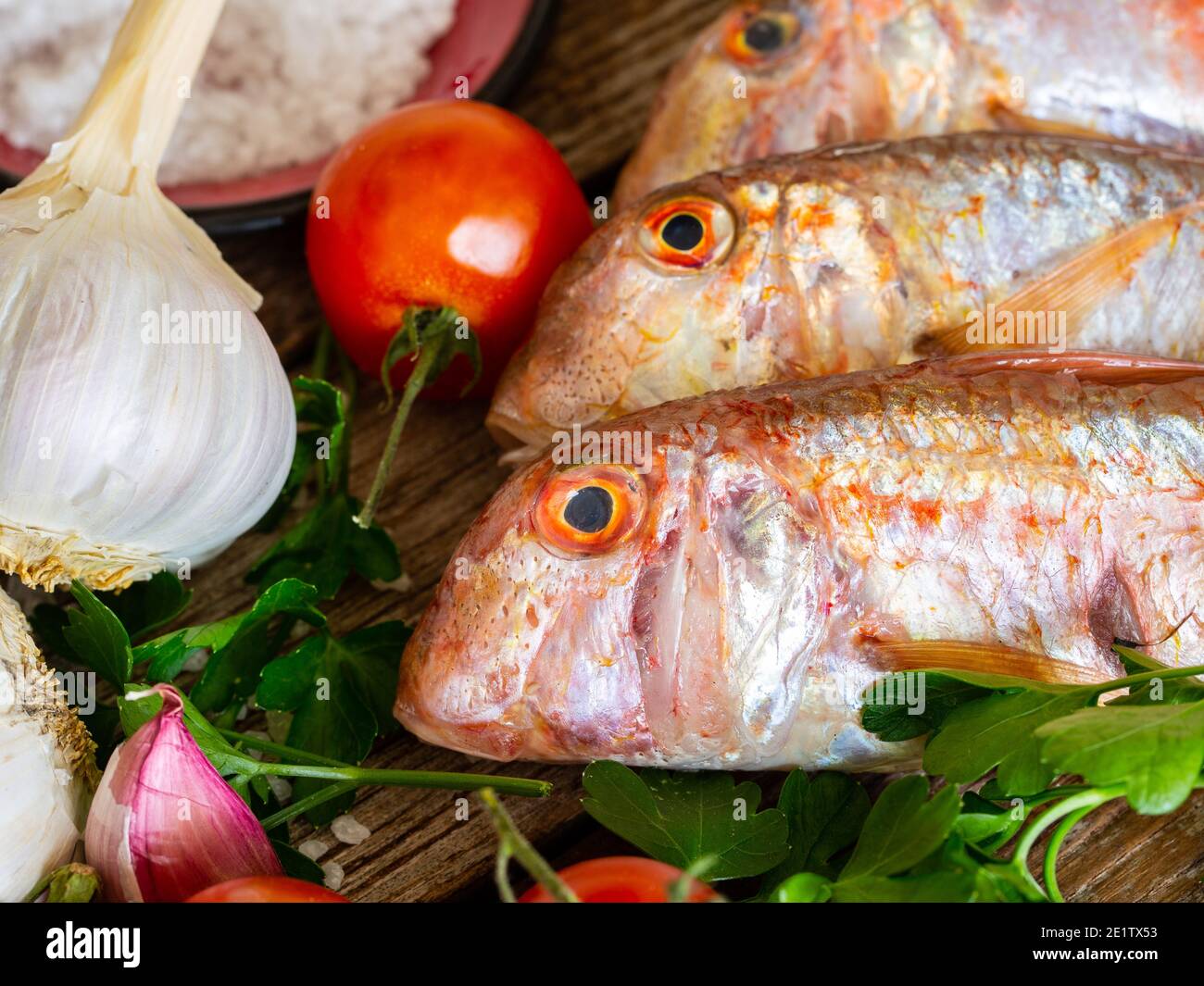 red mullet on an old wooden board background with typical ingredients ...