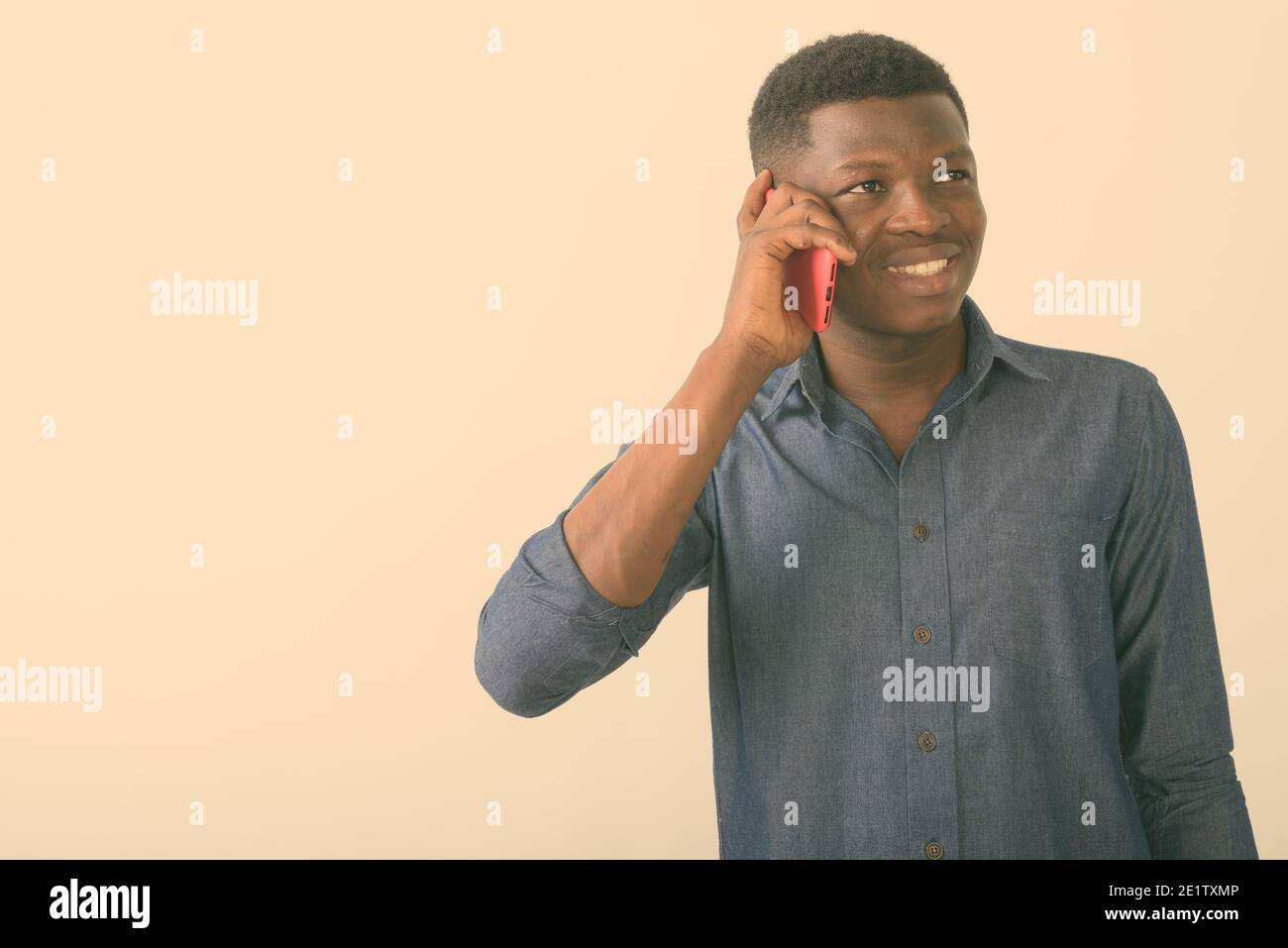 Studio shot of young happy black African man smiling and thinking while ...
