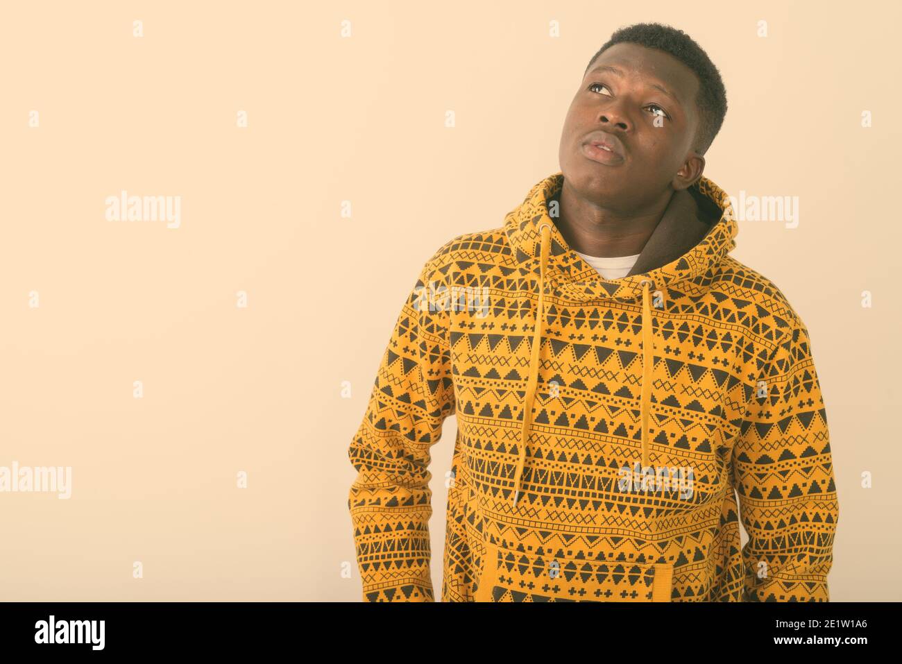 Studio shot of young black African man thinking while looking up ...