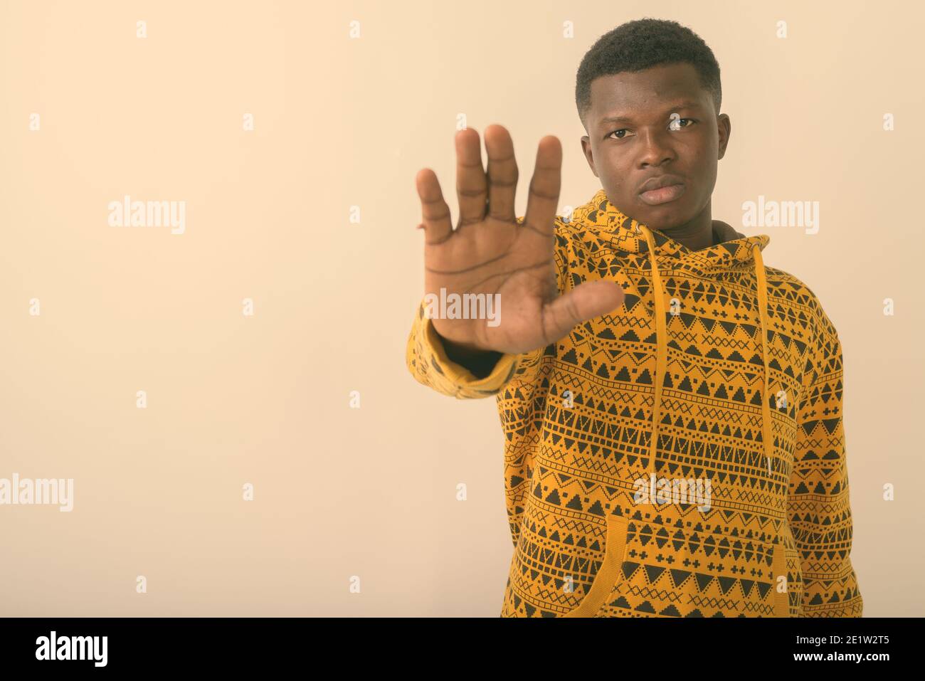 Studio shot of young black African man showing stop hand sign against ...