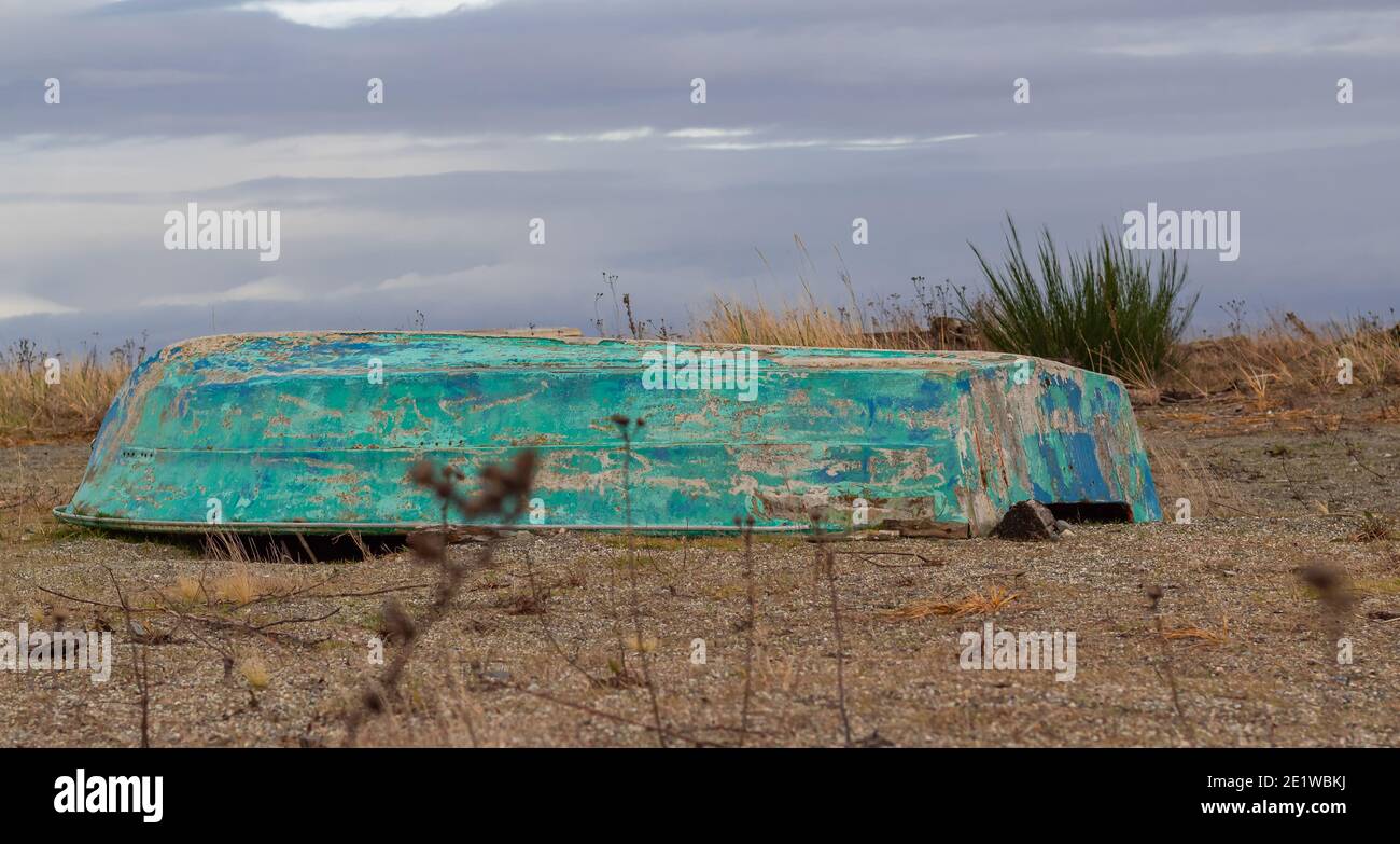 The old inverted green color boat lies on the sea shore in cloudy day ...